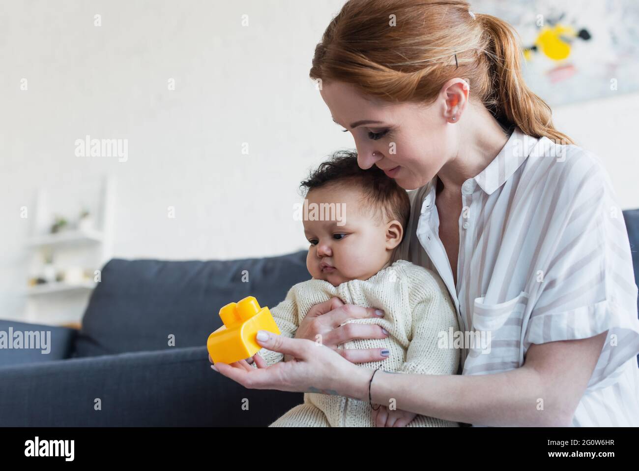 mother holding building block near little african american daughter ...