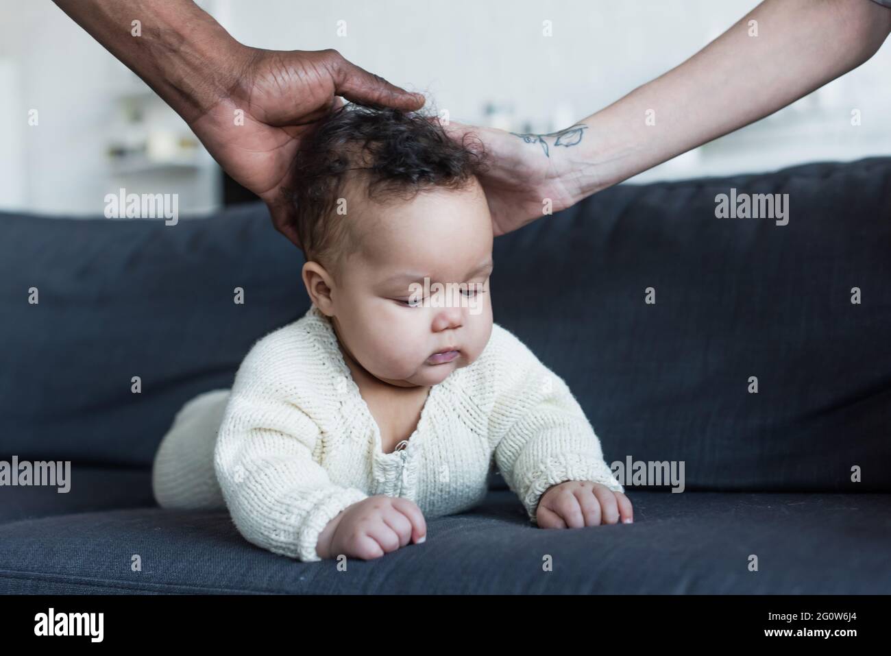 multiethnic parents touching head of african american baby crawling on ...