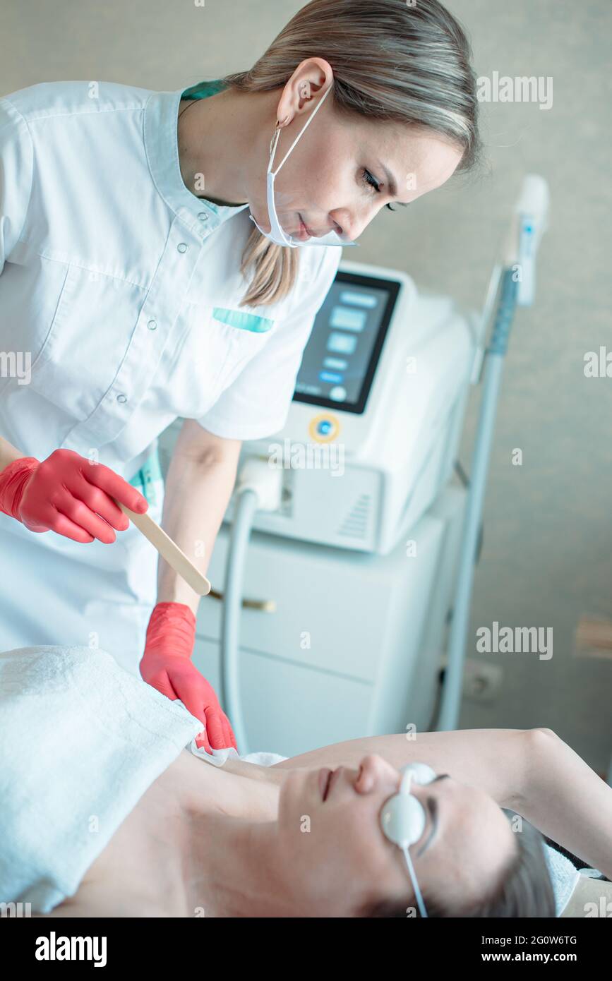 A woman beautician makes a diode laser epilation procedure. Laser hair ...