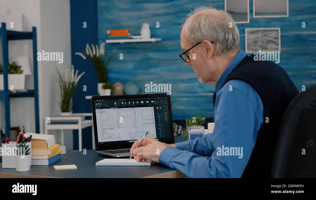 Senior man architect analysing digital prototype with plans from laptop ...
