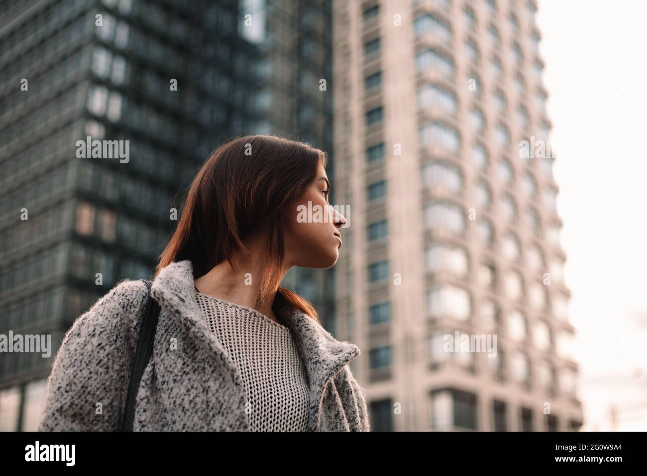 Thoughtful non-binary woman standing on street in city Stock Photo - Alamy