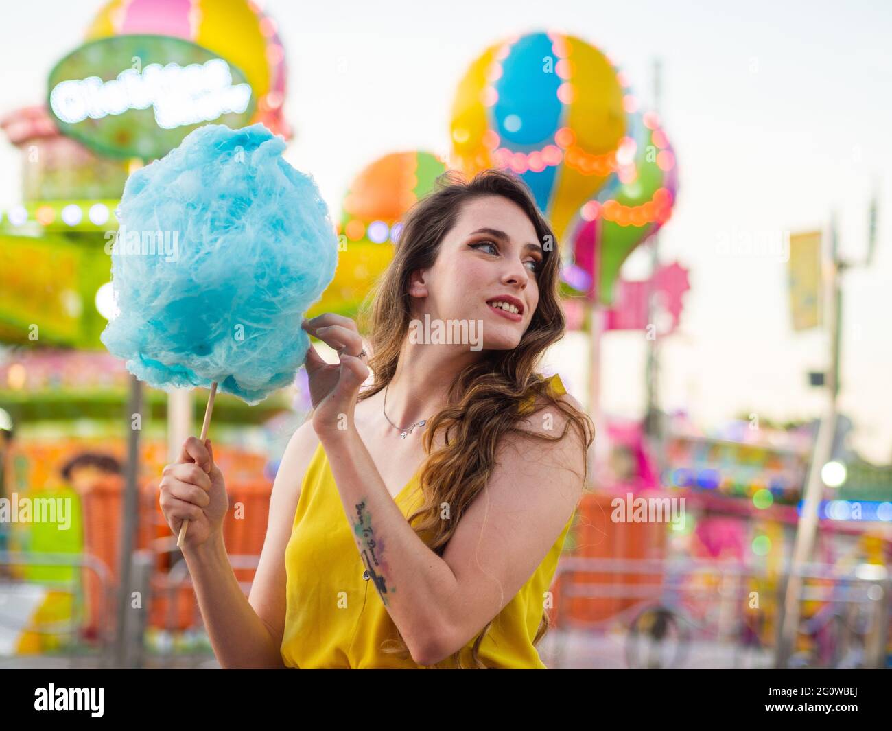 Attractive Caucasian female posing with blue cotton candy at a carnival ...