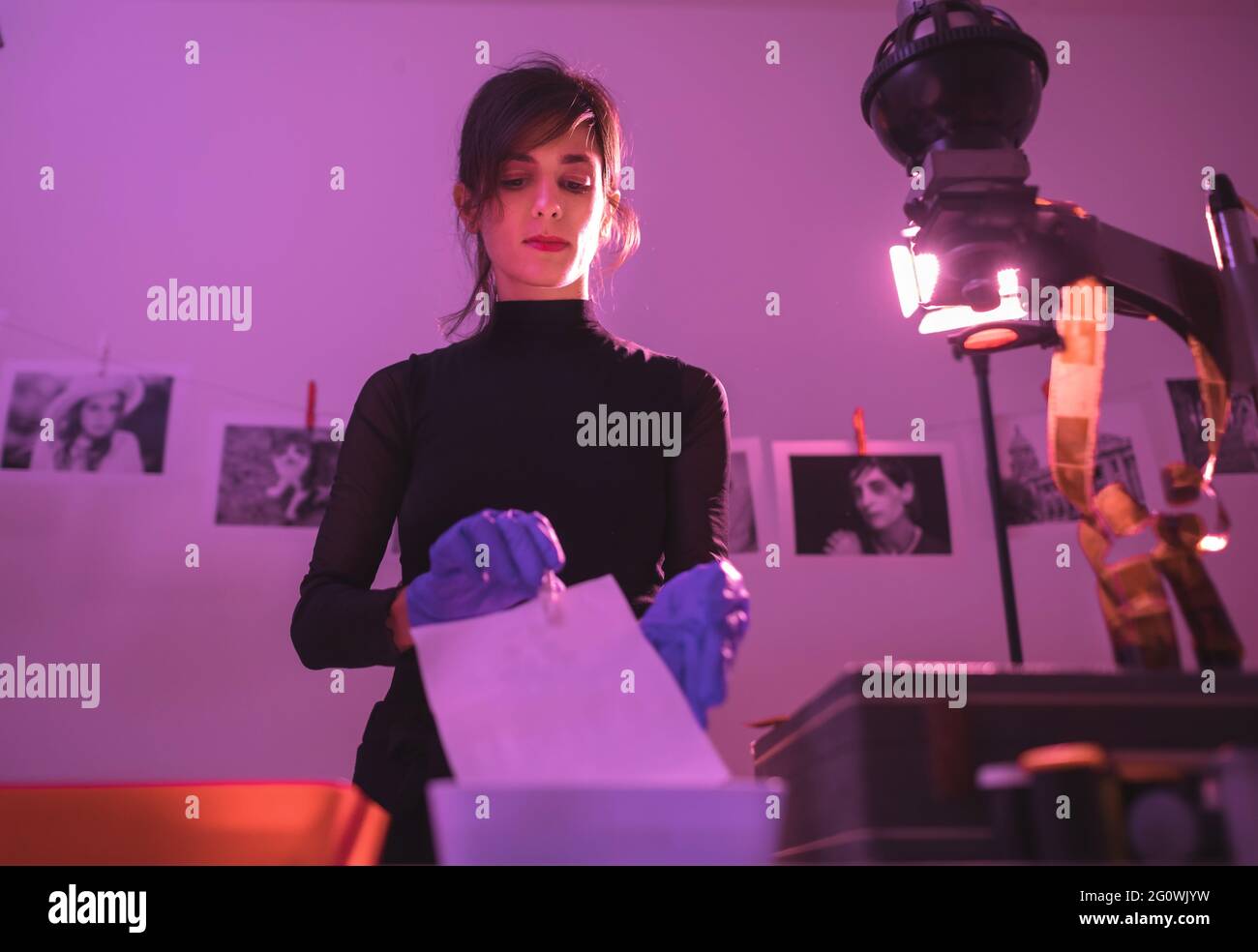 Female photographer developing film and printing photographs in ...