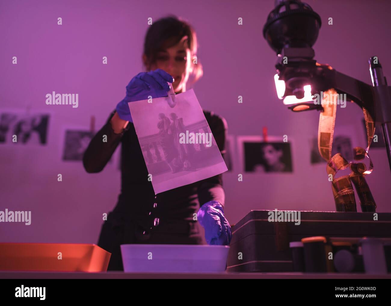 Female photographer developing film and printing photographs in ...