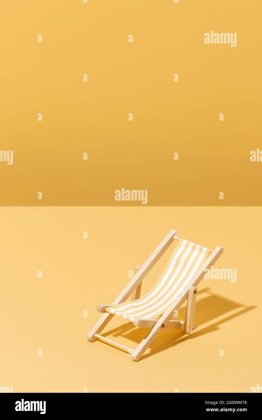 A yellow striped beach chair for sunbathing on a yellow background ...