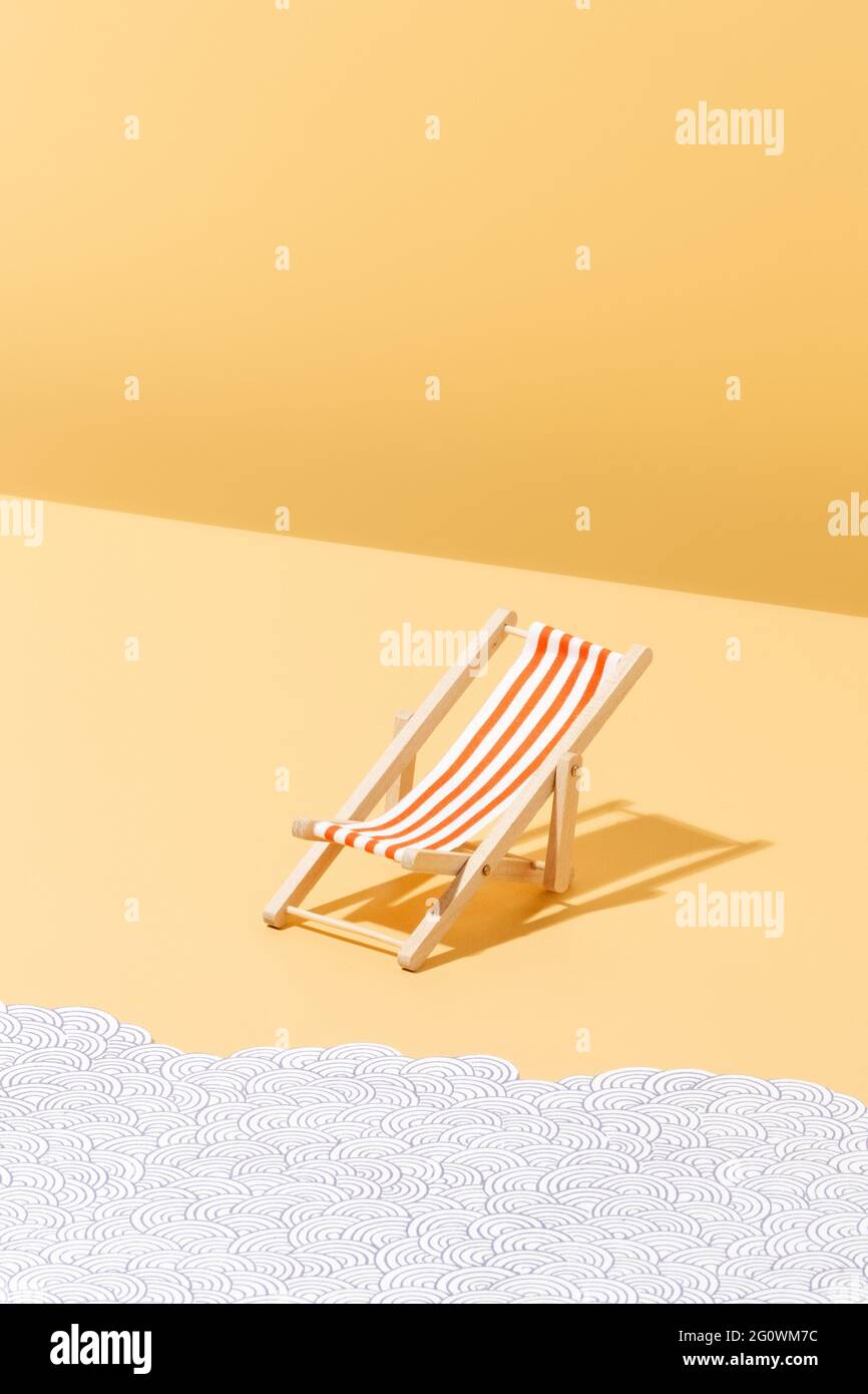 A red striped beach chair for sunbathing on a yellow background and ...