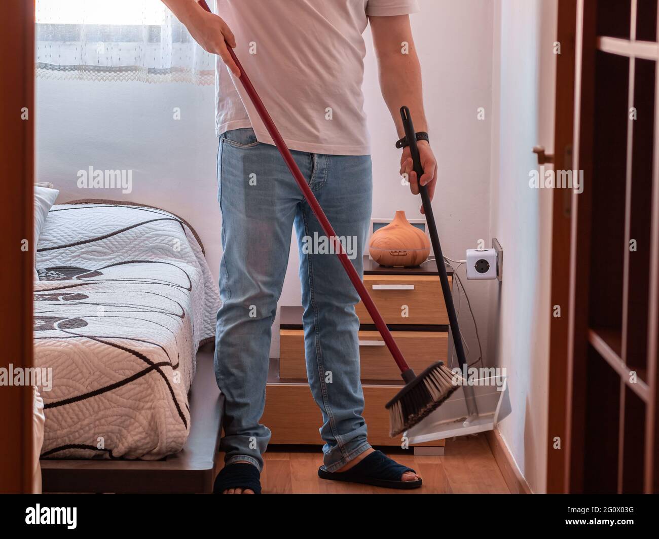 Utility man with a broom and dustpan cleaning the floor Stock Photo - Alamy