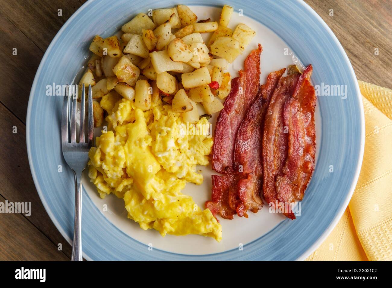 American breakfast food scrambled eggs with home fries and crispy bacon Stock Photo - Alamy