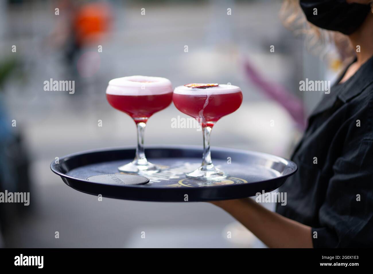 masked waitress carries two cosmopolitan cocktails on a tray Stock ...