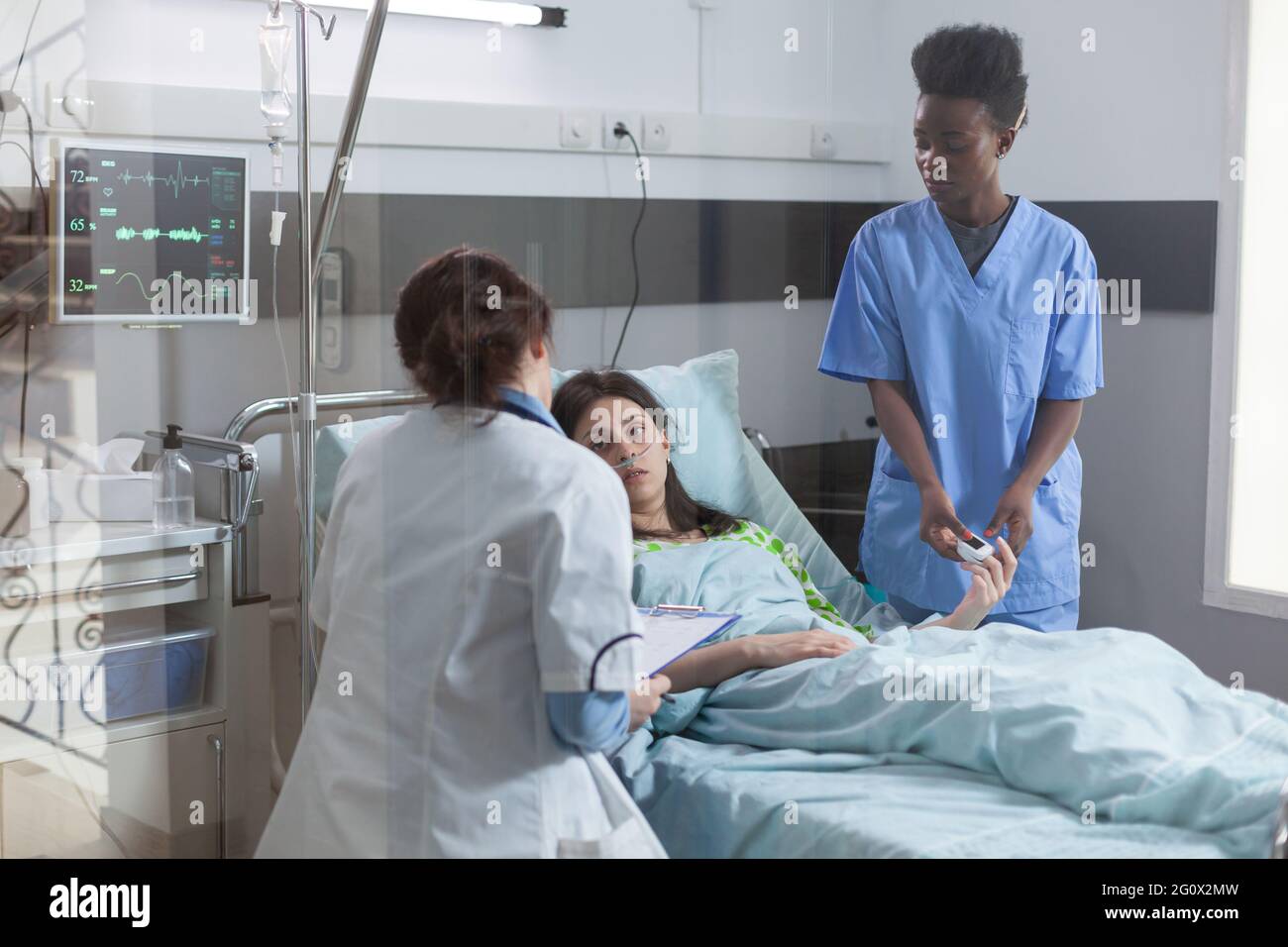 Patient resting in bed during recovery consultation while medical team ...
