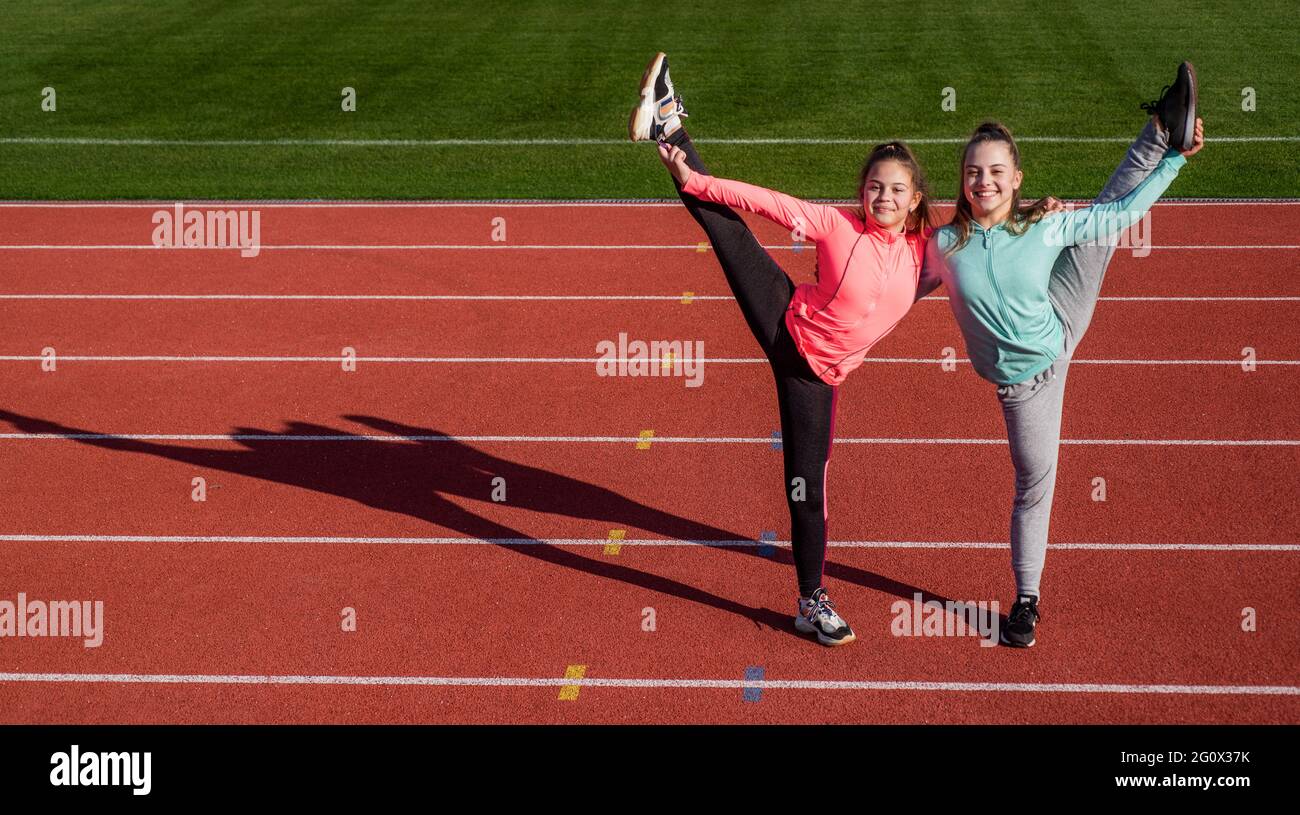 Happy teenage gymnasts do vertical splits holding legs at athletics ...