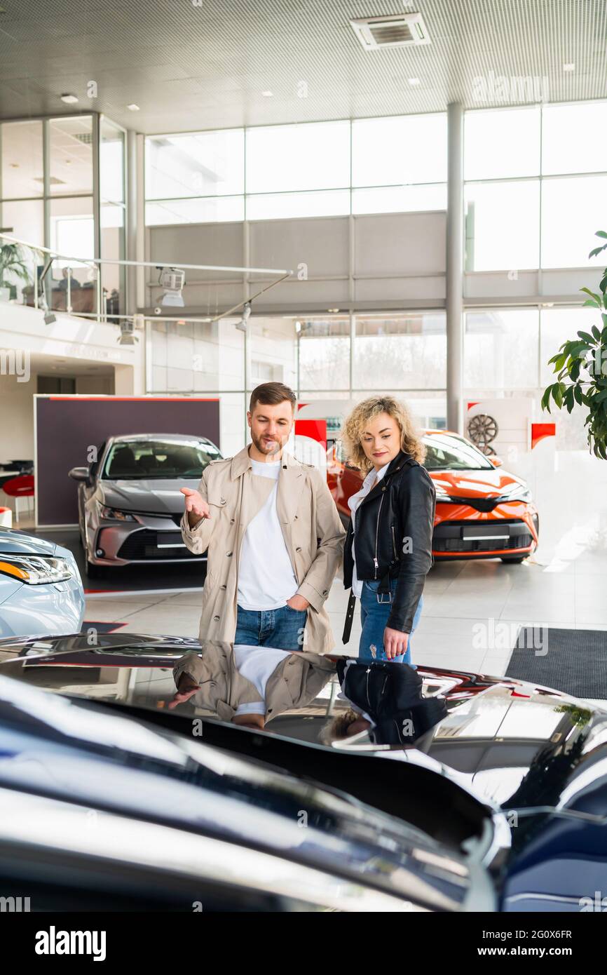 Beautiful couple in car dealership chooses car Stock Photo - Alamy