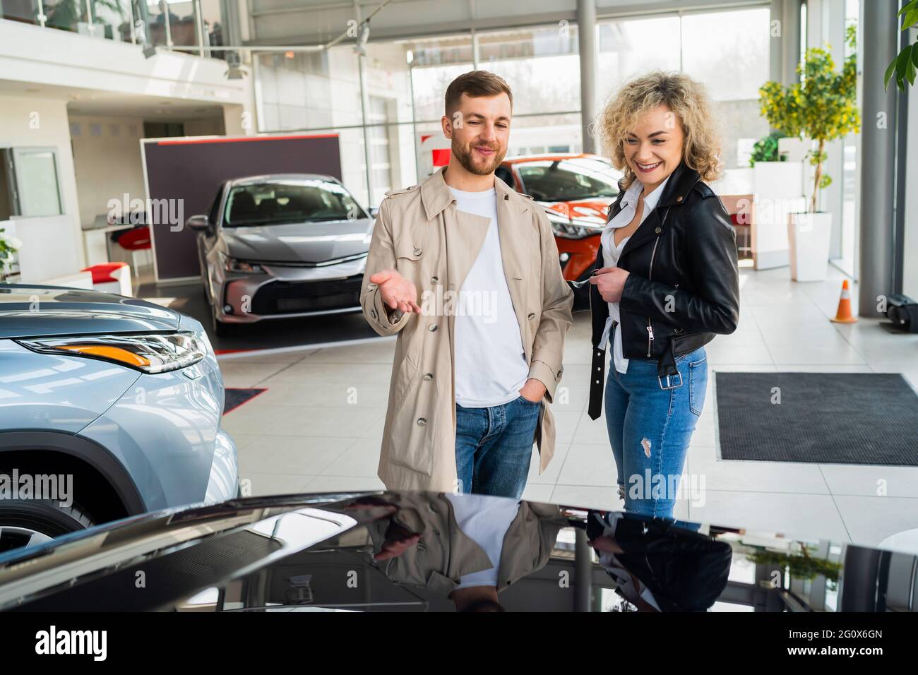 Beautiful couple in car dealership chooses car Stock Photo - Alamy