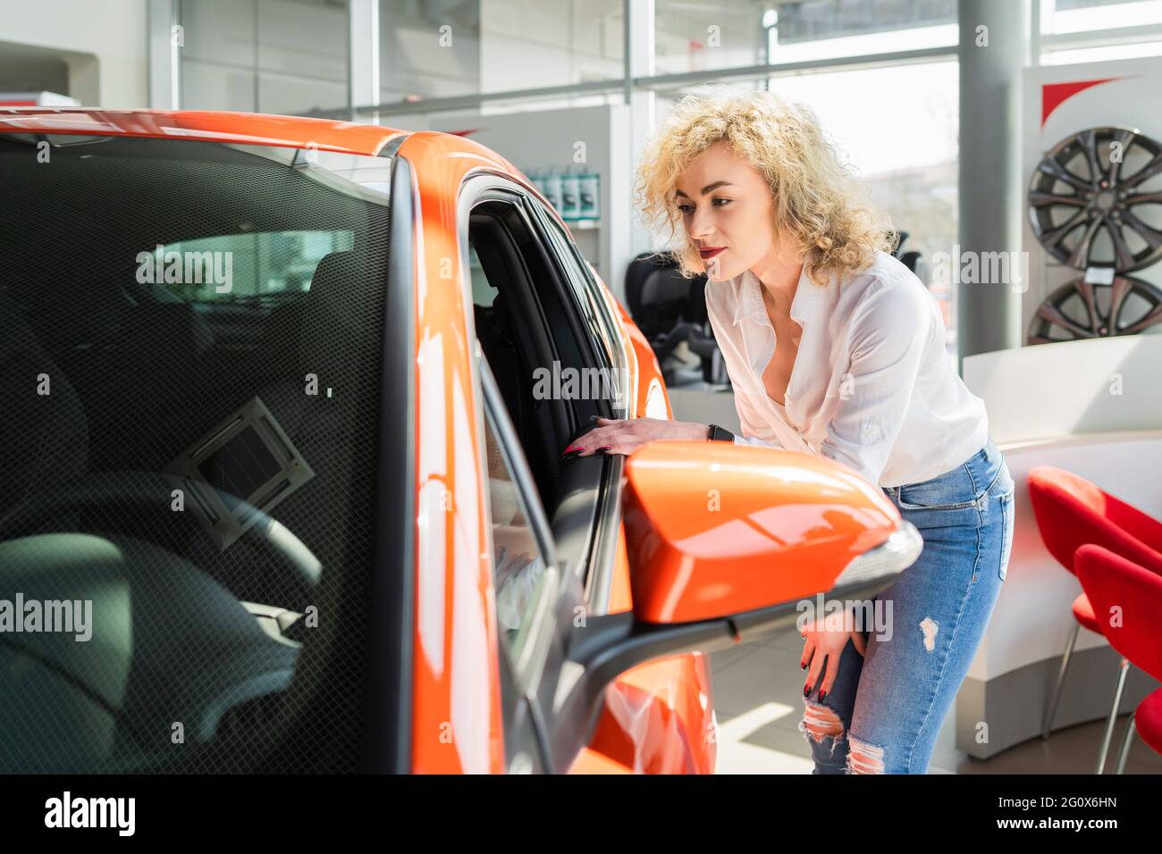Curly woman looks car at the dealership Stock Photo - Alamy