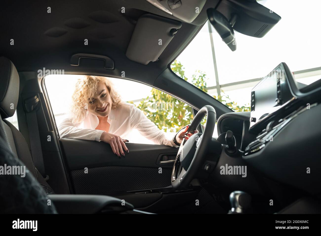 Girl looks inside the car through the window. Woman chooses a new auto ...