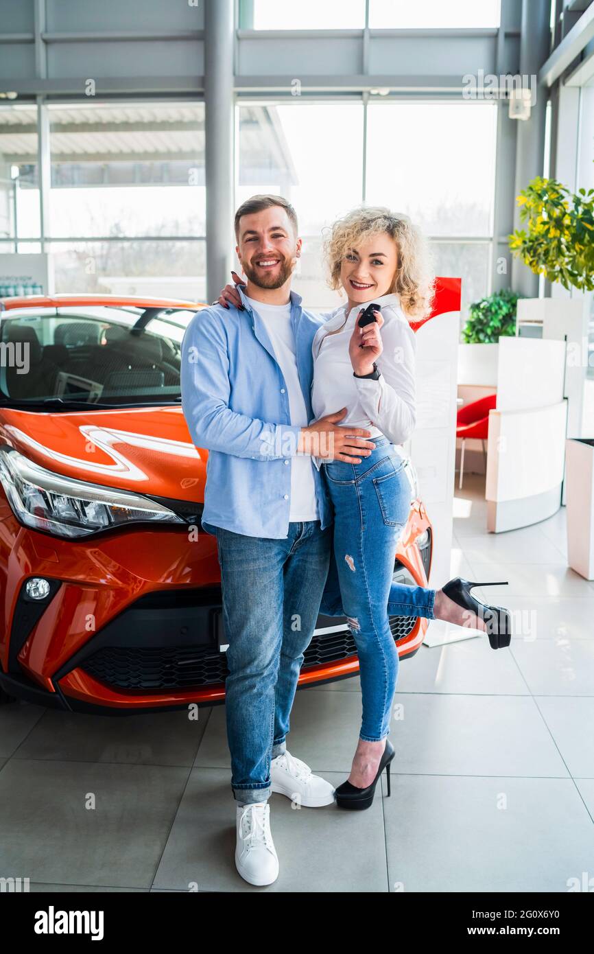Happy couple in car dealership on the background of their new car Stock ...