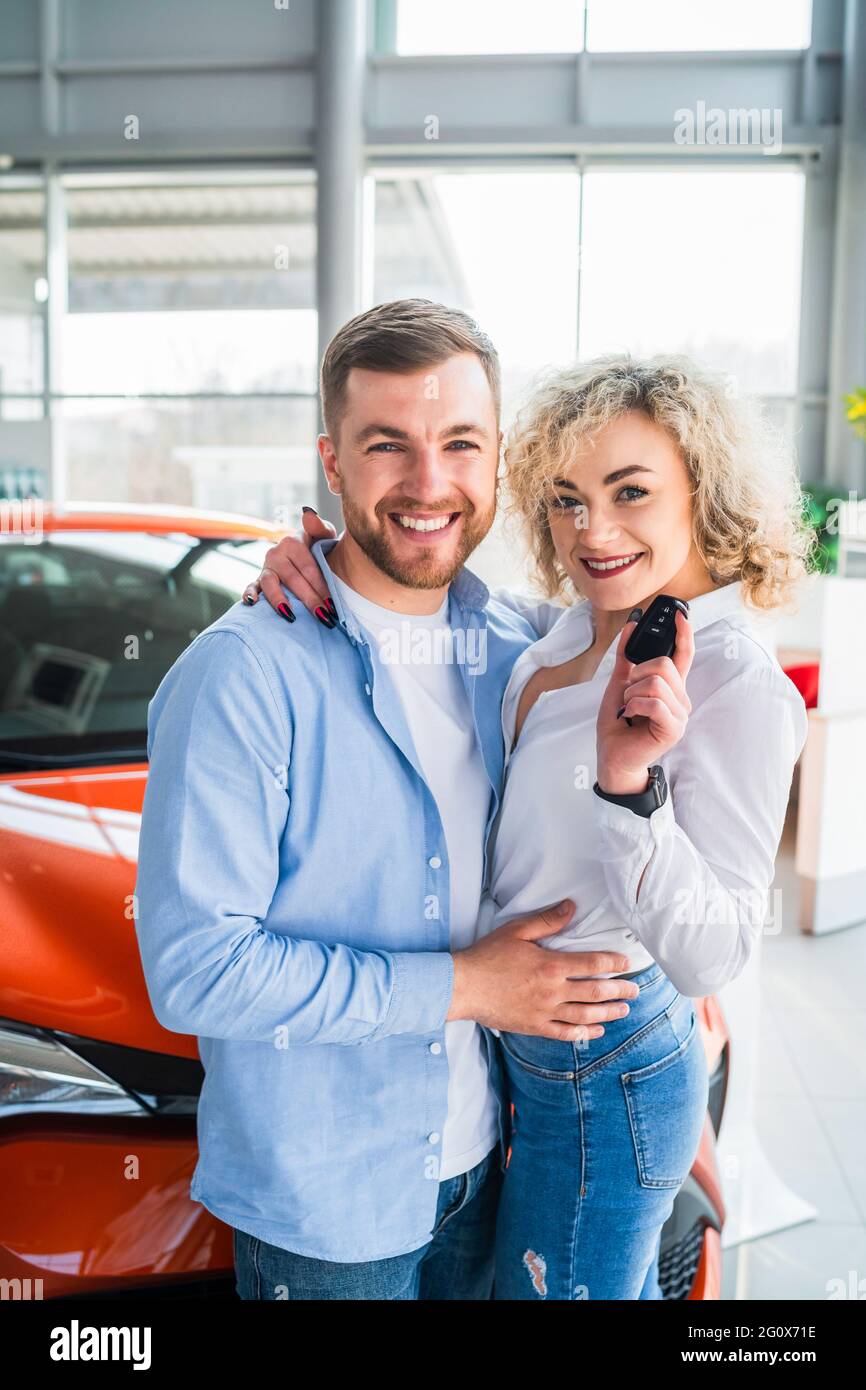 Happy couple in car dealership on the background of their new car Stock ...