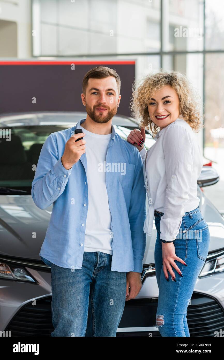 Happy couple in car dealership on the background of their new car Stock ...