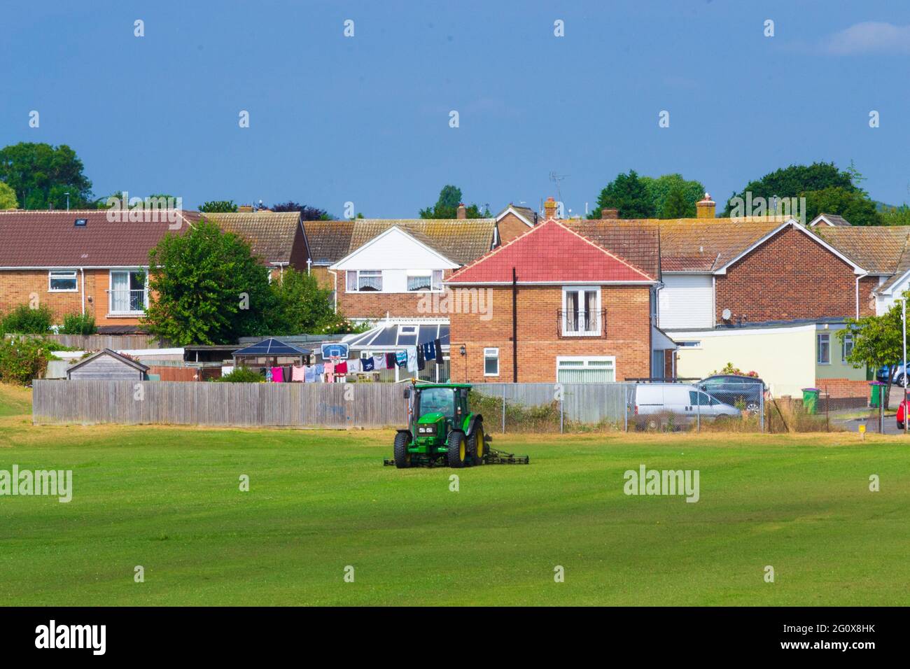 Tractor mows the lawn of a playground at Folkestone town ,Kent,England ...