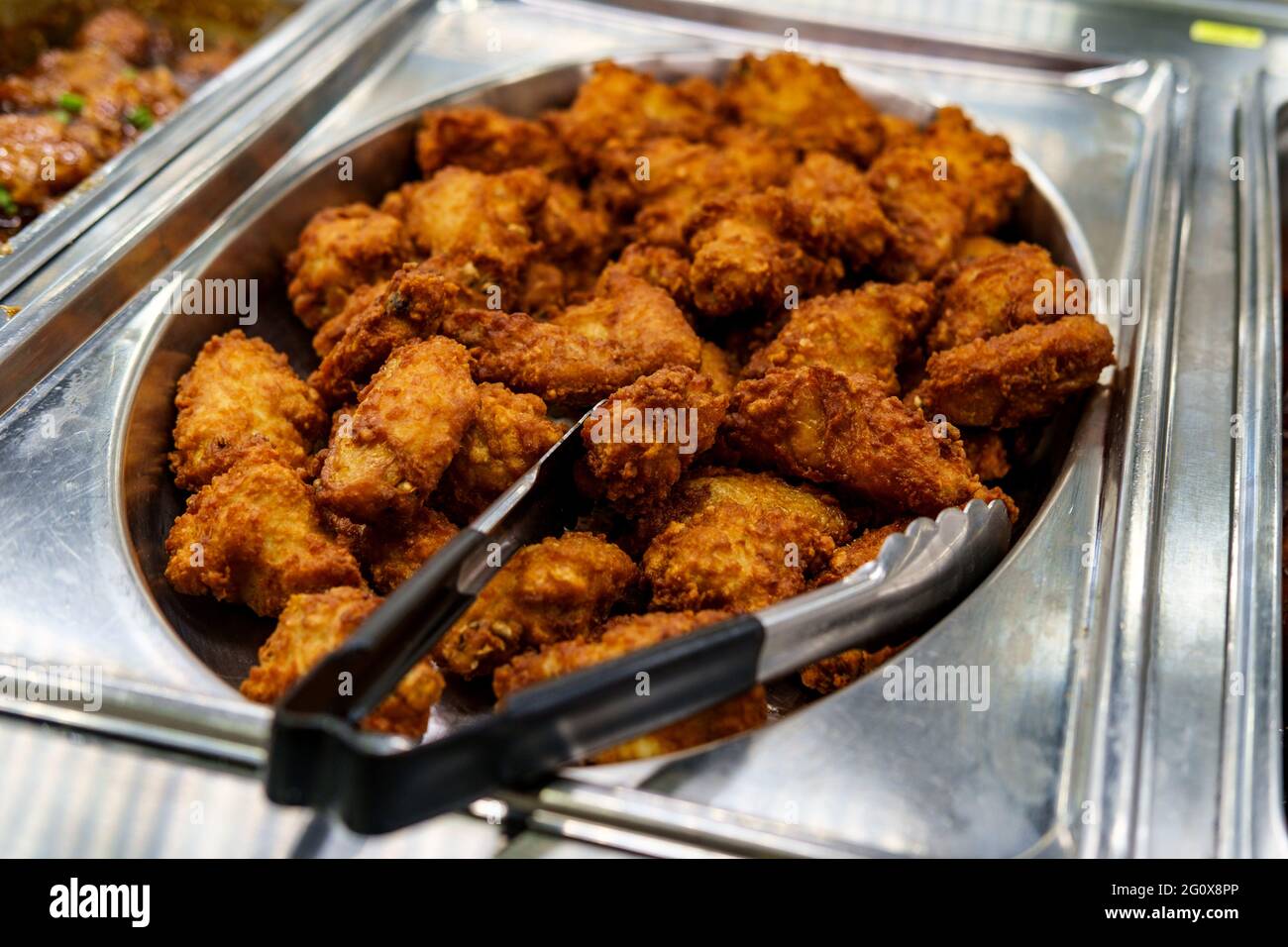 Fried chicken wings buffet station with serving tongs Stock Photo - Alamy