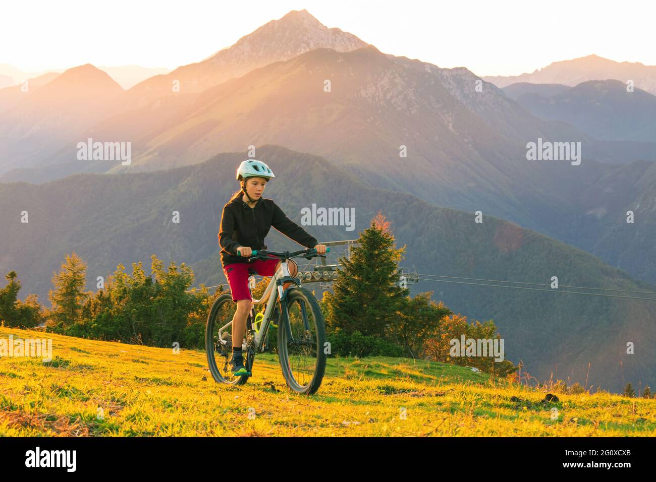 Girl child riding mountain bike into the sunset. Beautiful golden ...