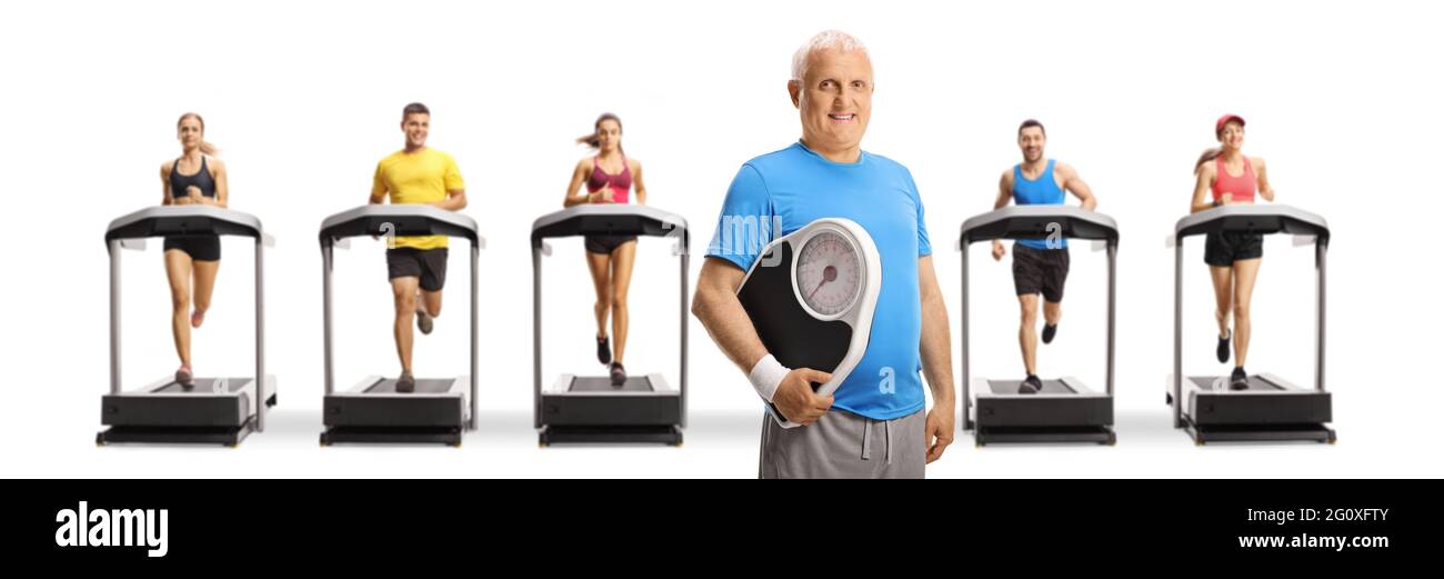 Mature man holding a weight scale in front of people running on ...