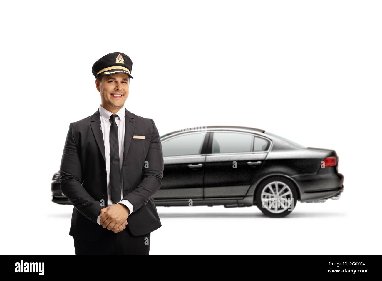 Young chauffeur standing in front of a black car isolated on white ...
