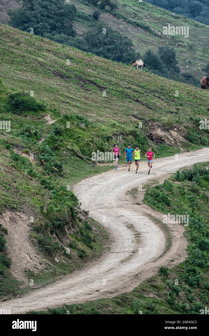 Group of runners running on a trail along beautiful mountain roads ...