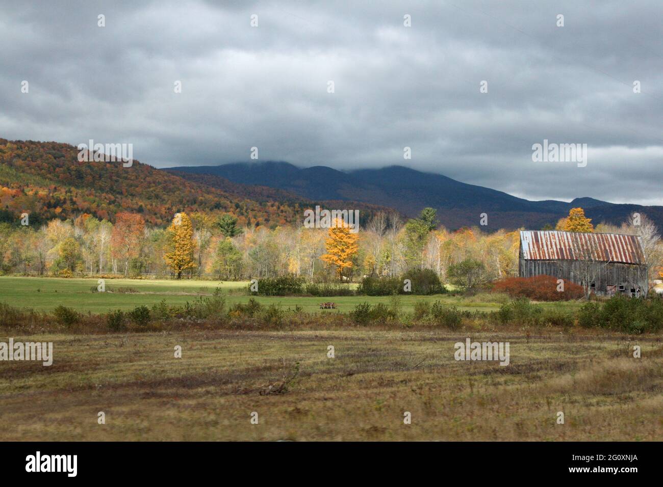 Dark storm clouds rolling over mountain top with trees and farm fields ...