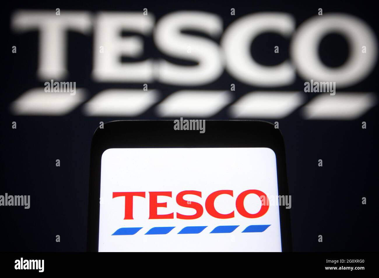 In this photo illustration, a Tesco logo is seen on a smartphone and a ...