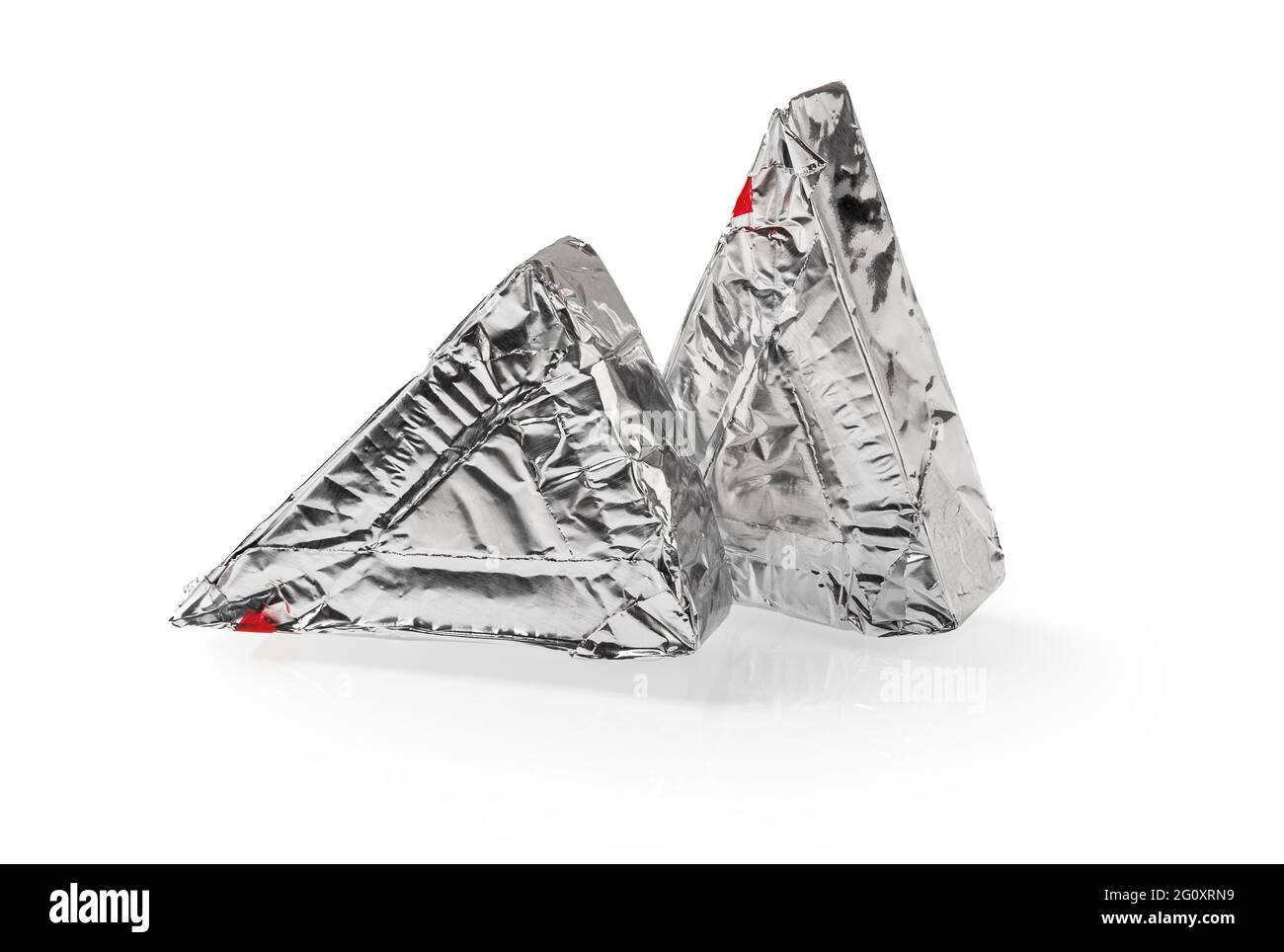 Two triangular pieces of foil wrapped processed creame cheese isolated ...