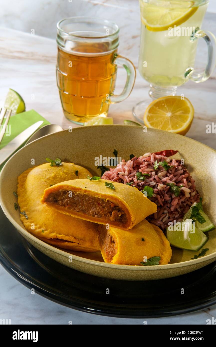 Spicy Jamaican beef turnovers with cilantro garnish and purple rice ...