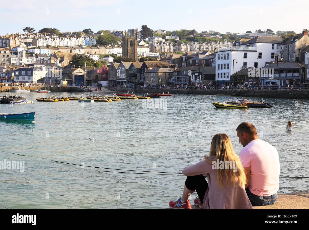 Sitting by the pretty harbour at St Ives, as the sun sets, in the ...
