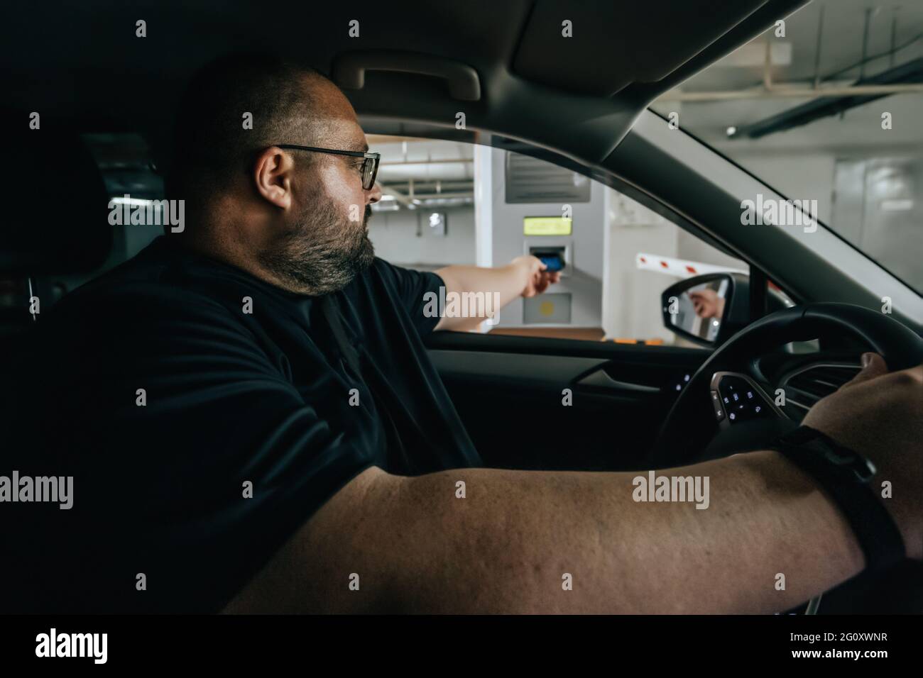 Man driving car leaves underground parking in mall by paying with card ...