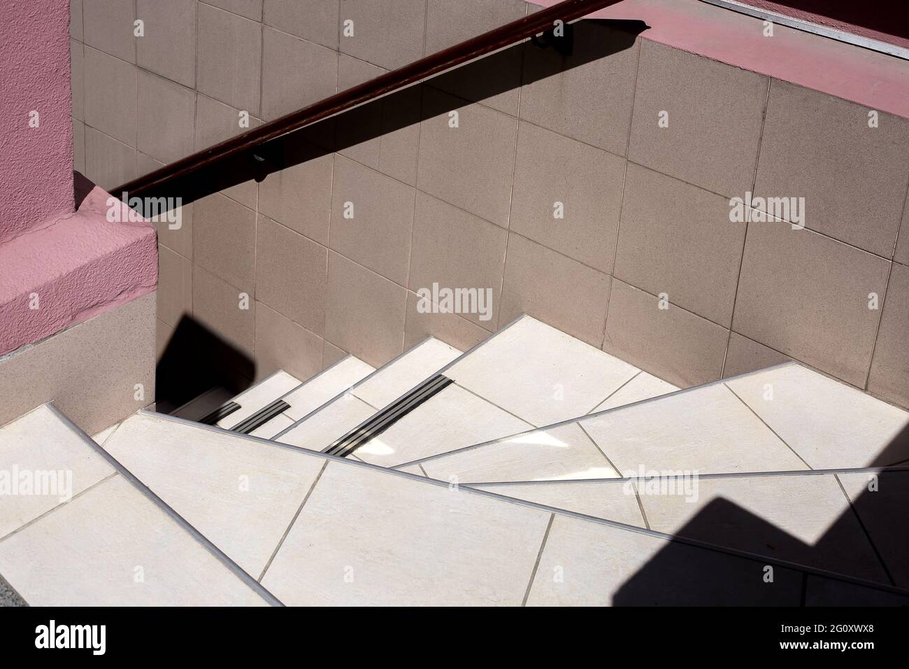 stairs downhill lined with ceramic tiles with a railing on the wall ...