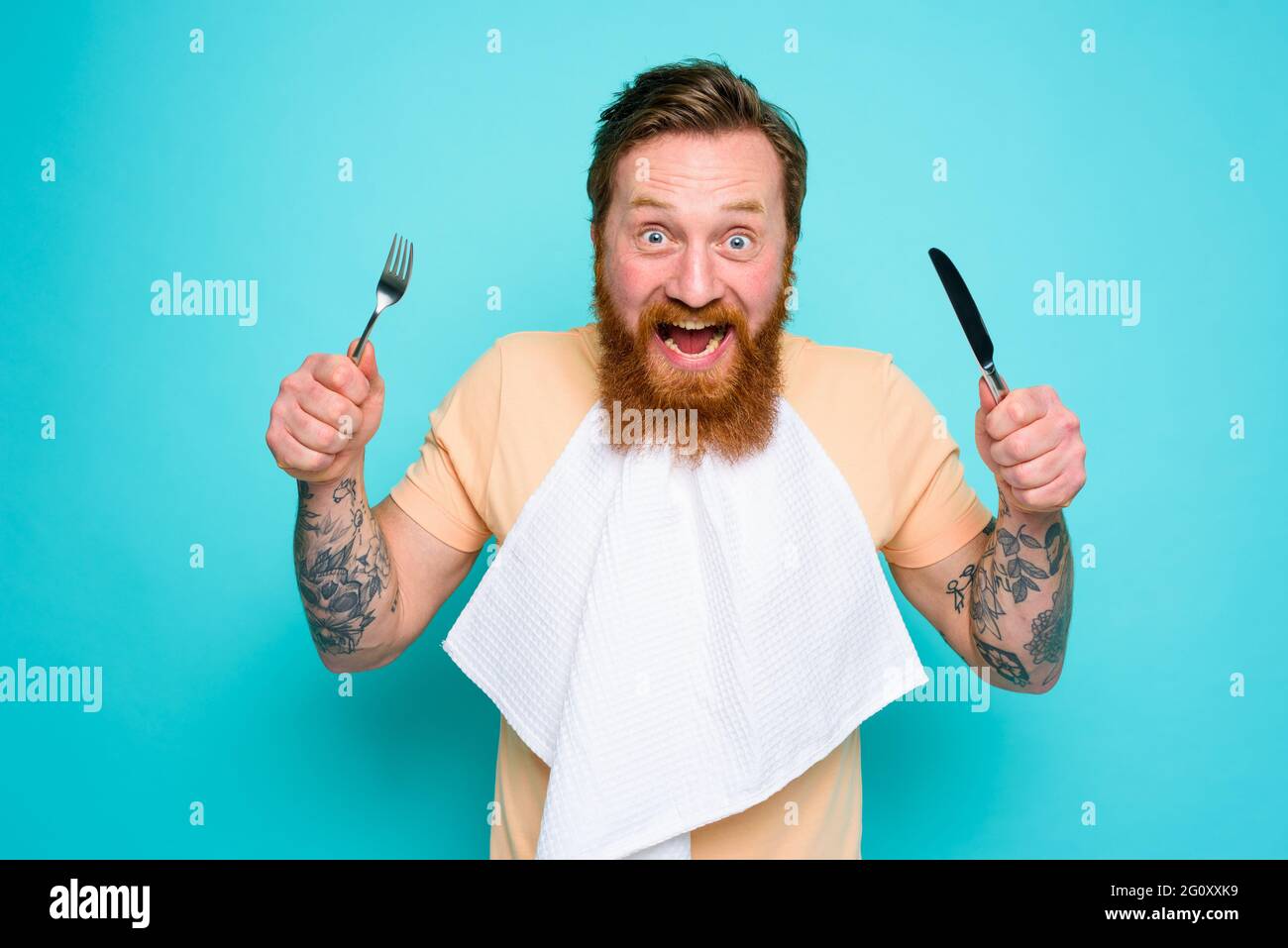 Hungry man with tattoos is ready to eat with cutlery in hand Stock ...