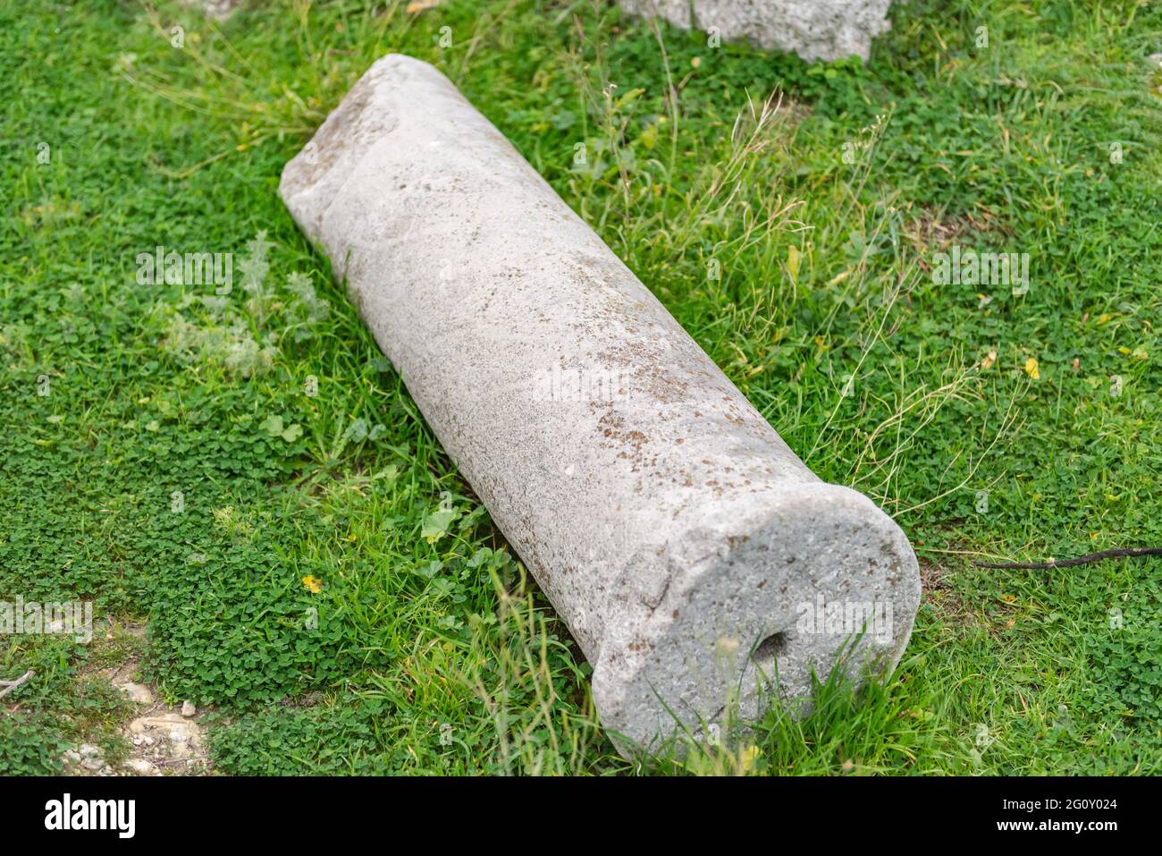 Old column on the grass. A stone pillar, all that remains of a thousand ...