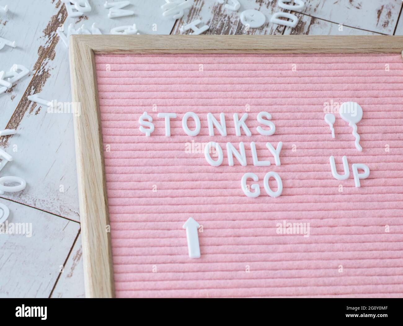 sign that says a joke about stocks that only go up on a pink felt board with a wooden frame and ...