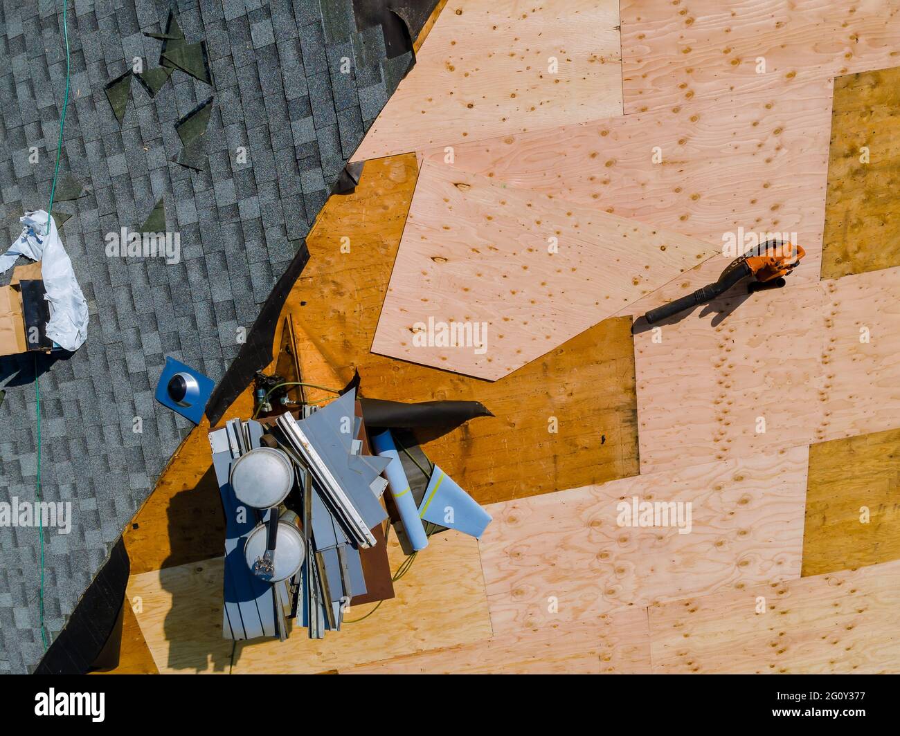 A worker replace shingles on the roof of a home repairing the roof of a home Stock Photo - Alamy