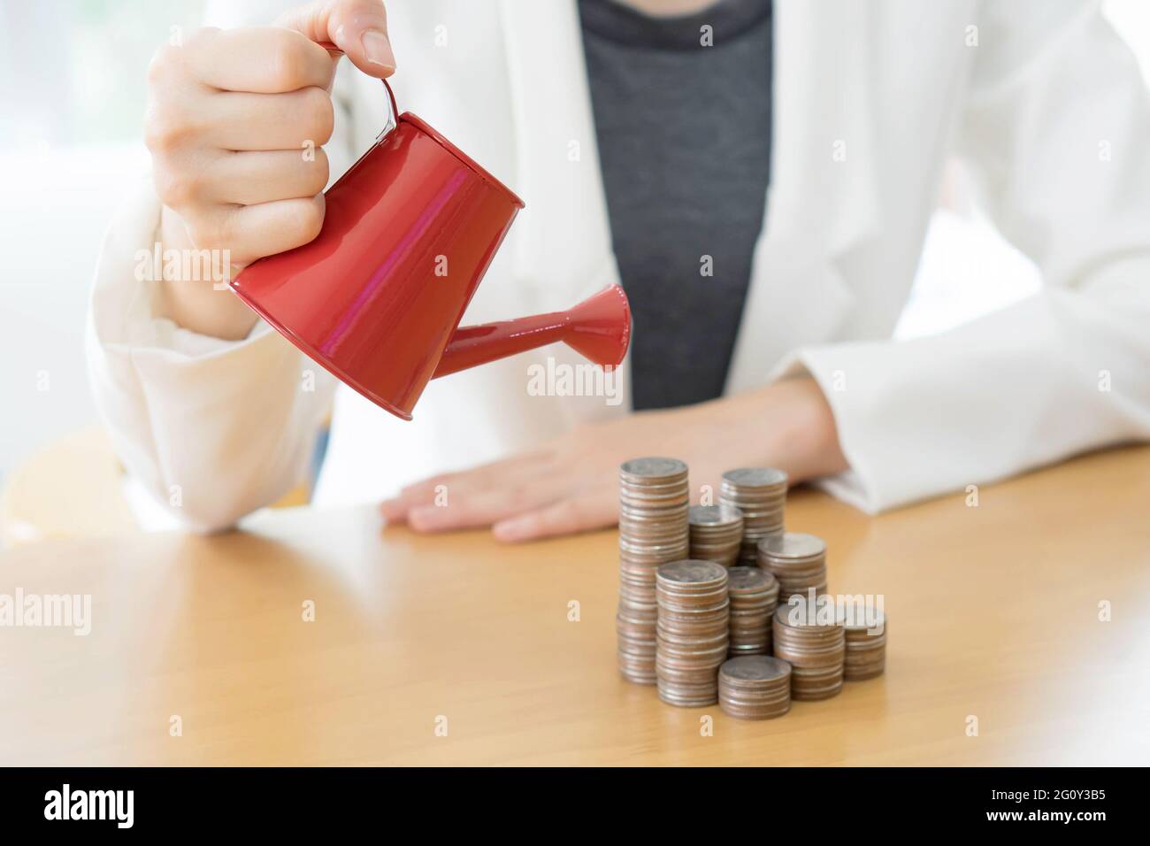 hand business woman and red watering can with money Stock Photo - Alamy