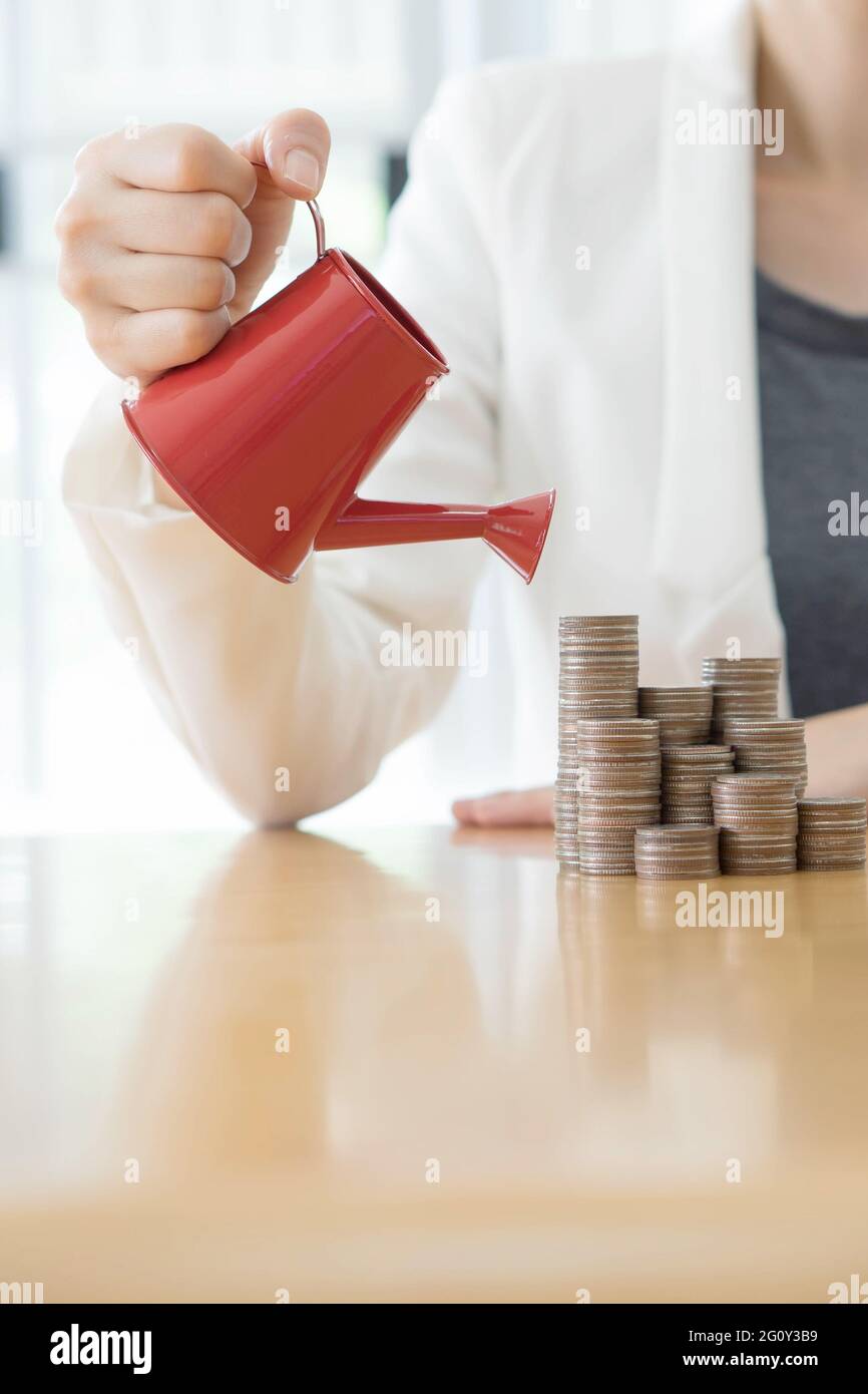 hand business woman and red watering can with money Stock Photo - Alamy