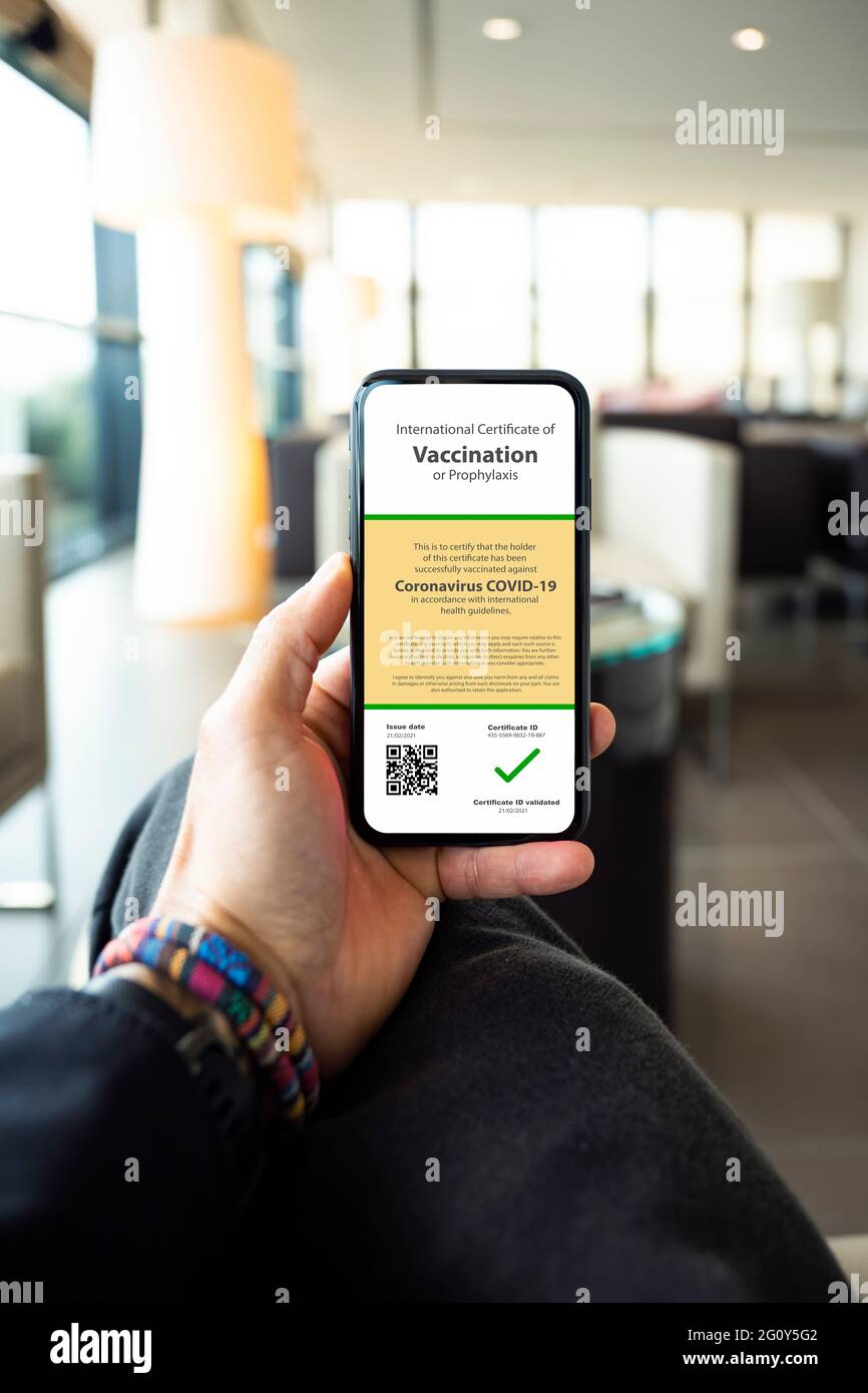 Human hand holding a smart phone with a Certificate of Vaccination ...