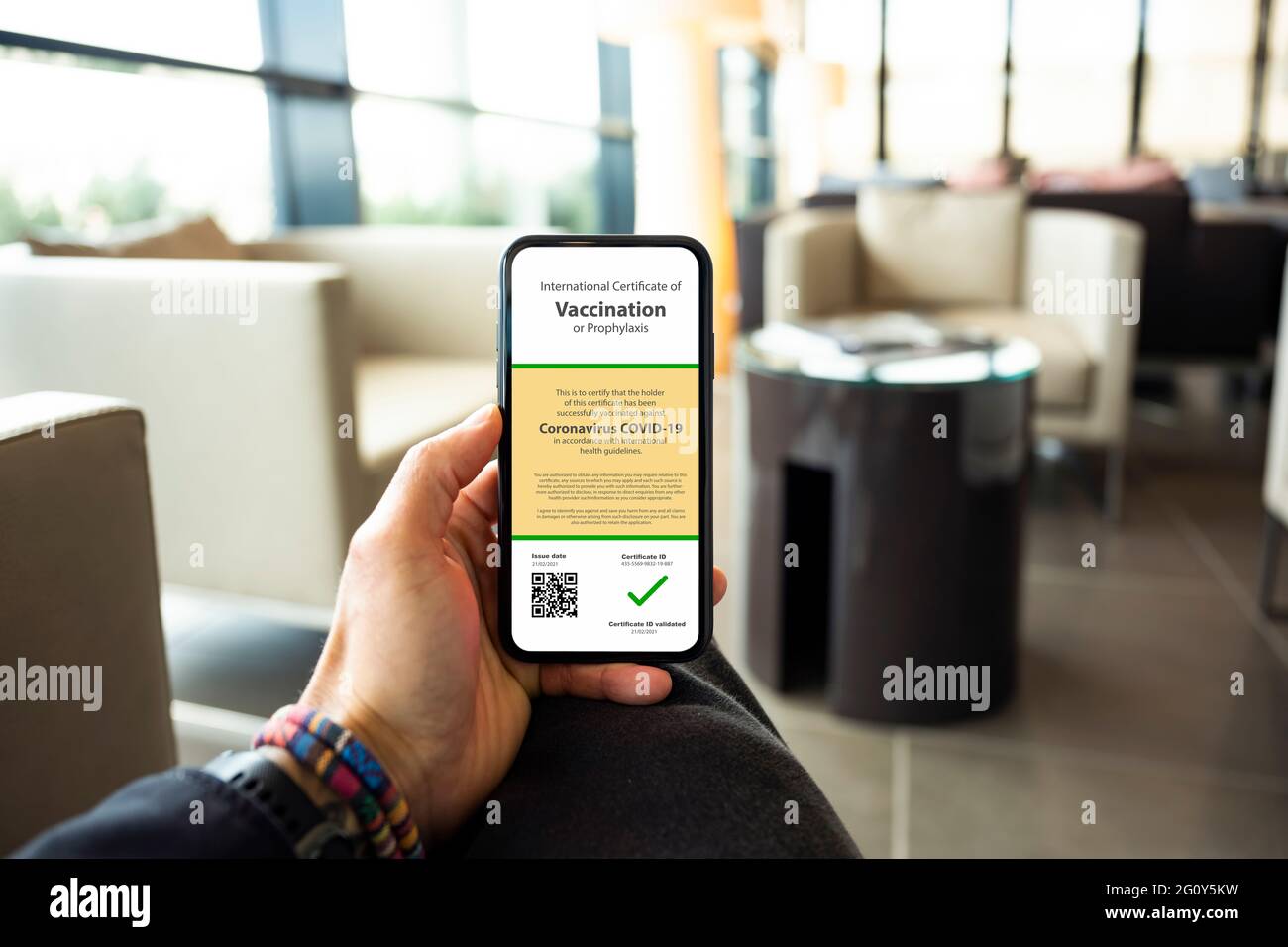 Human hand holding a smart phone with a Certificate of Vaccination ...