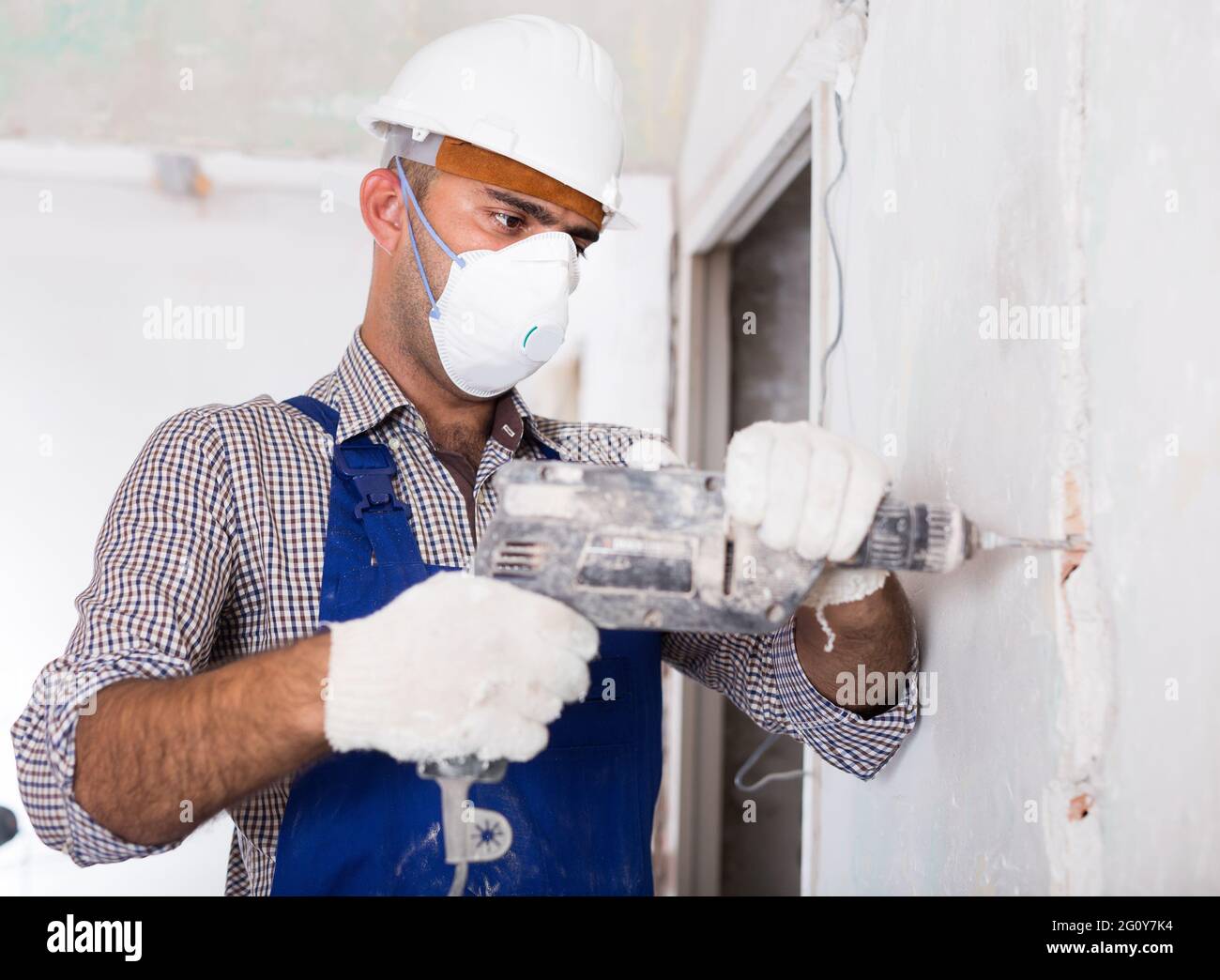 Adult male worker repairing with drill in mask Stock Photo - Alamy
