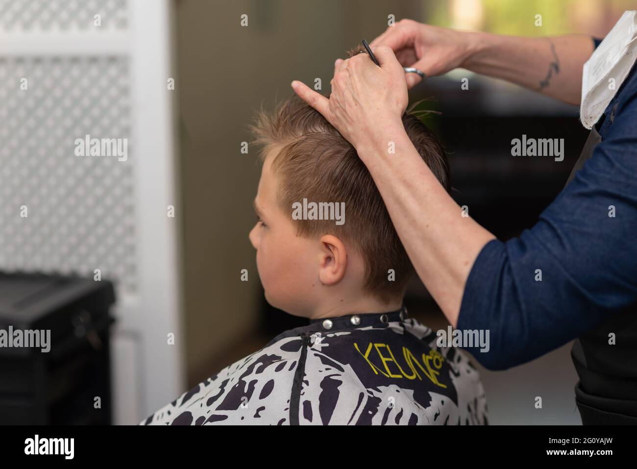 Cutting hair for young boy in a beauty salon. Hand with instrument used ...