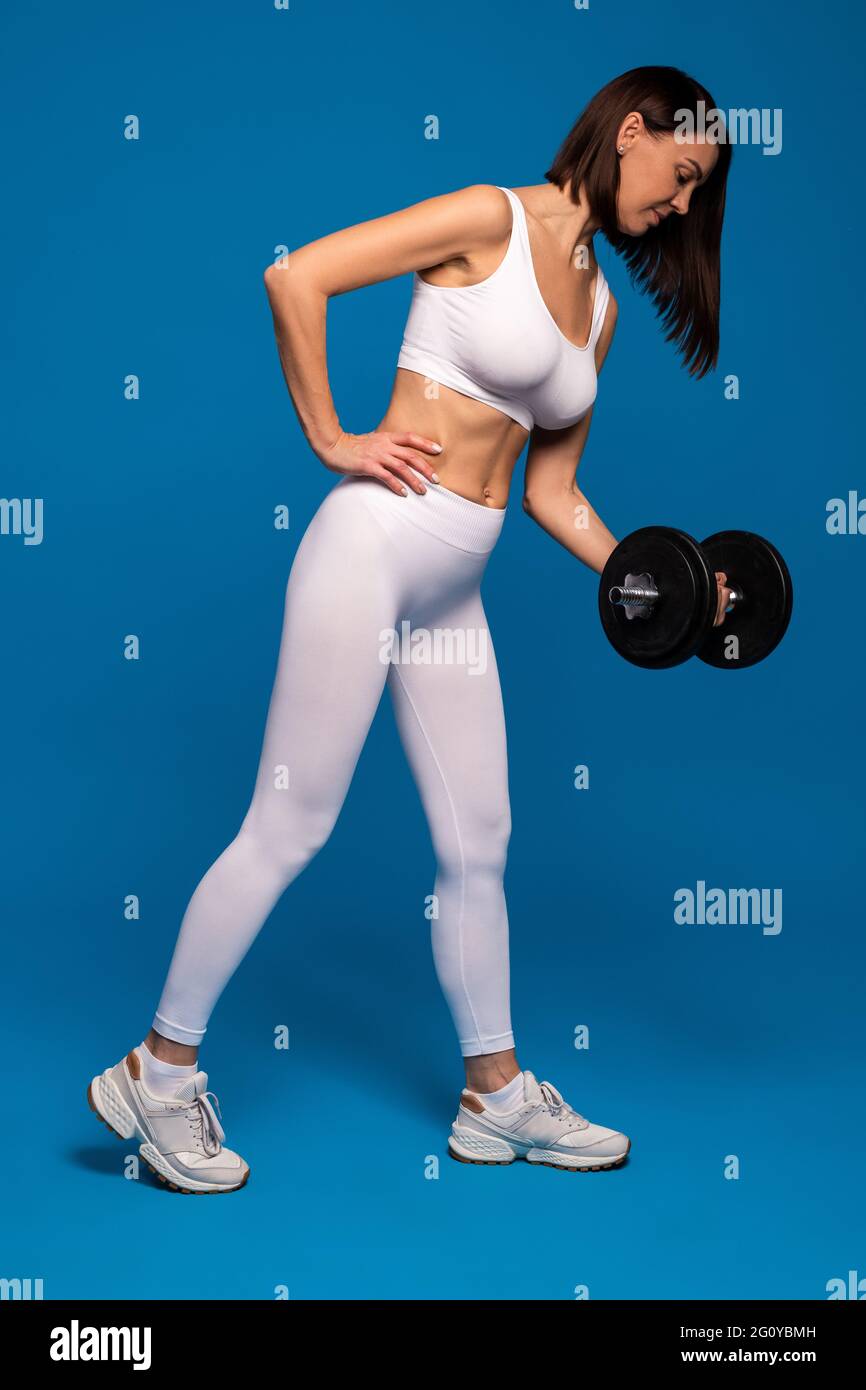 Woman one arm bicep curl with dumbbell on blue background Stock Photo - Alamy