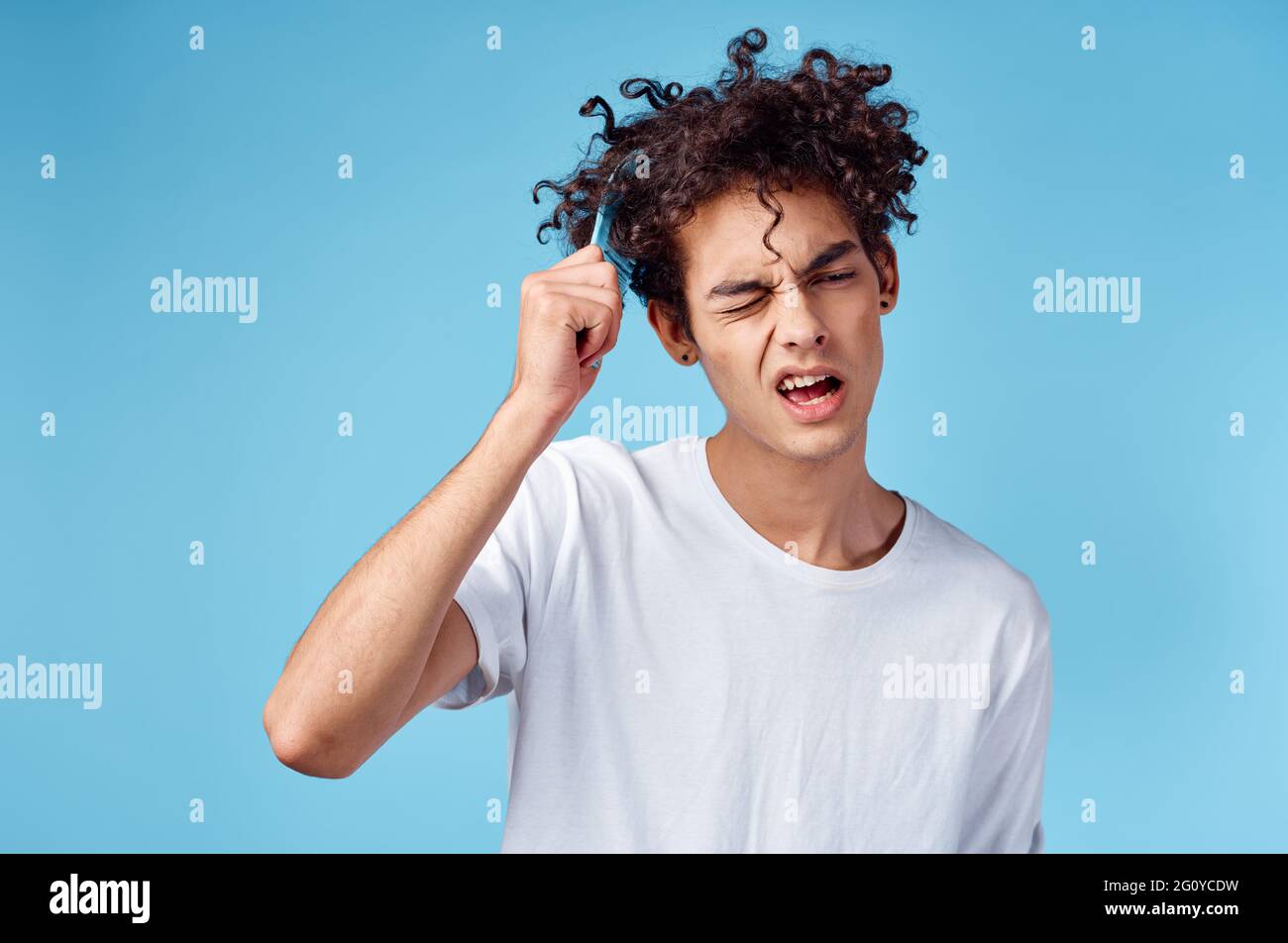 handsome guy with curly hair on a blue background portrait close-up ...