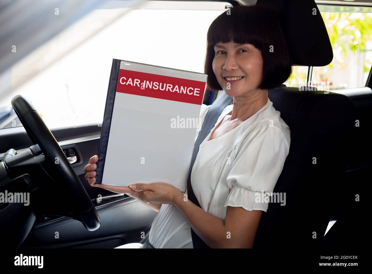 Happy Asian senior woman holding car insurance document book and ...
