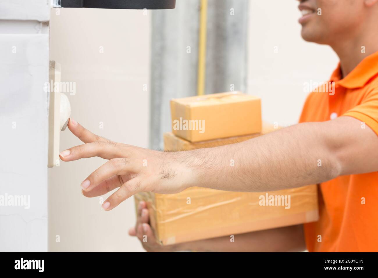Asian man with parcel box ringing customers doorbell. Delivery man in ...