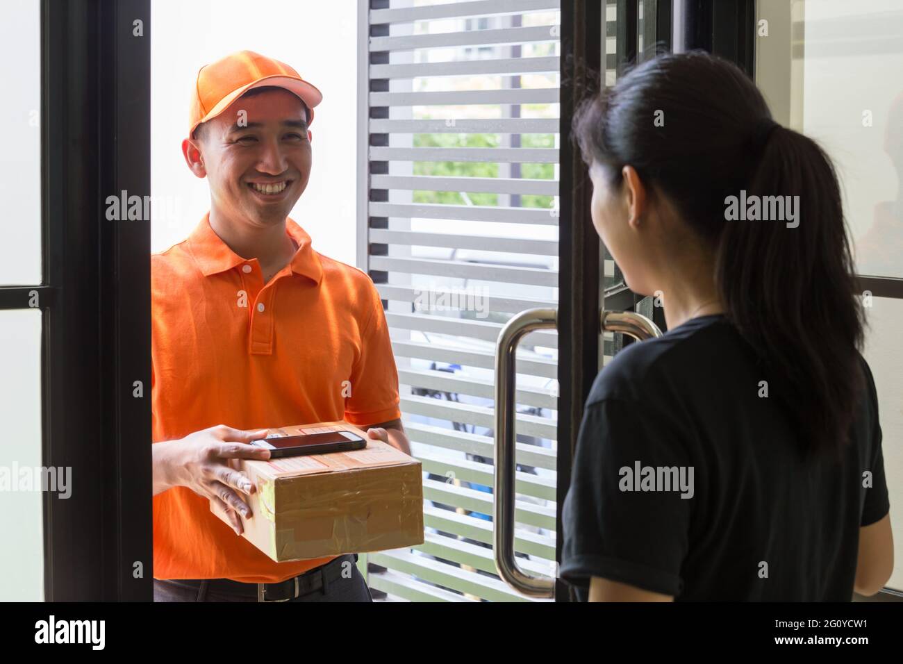 Women customer open the door for receive parcel from delivery man Stock ...